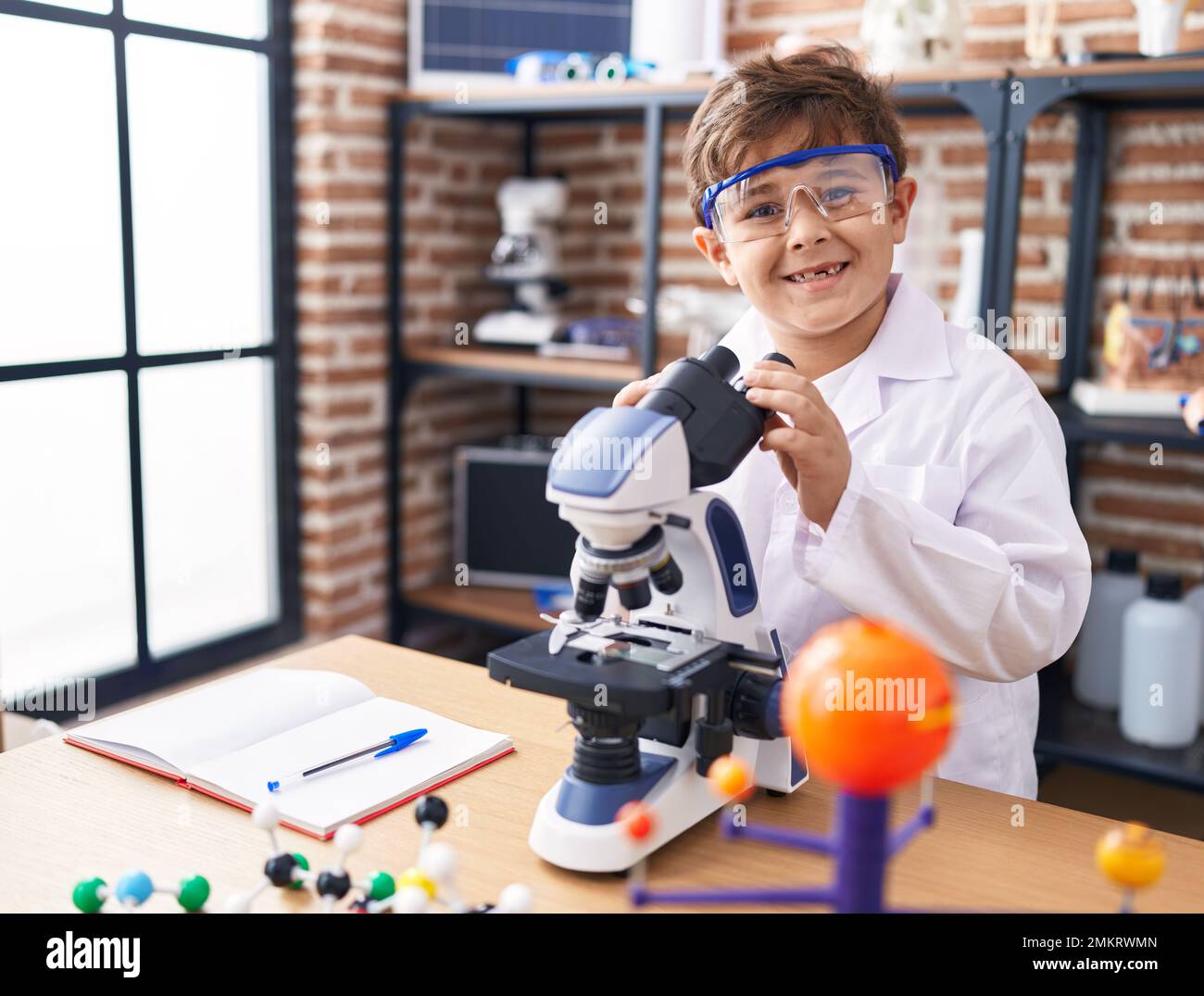 Adorable hispanic boy student smiling confident using microscope at ...