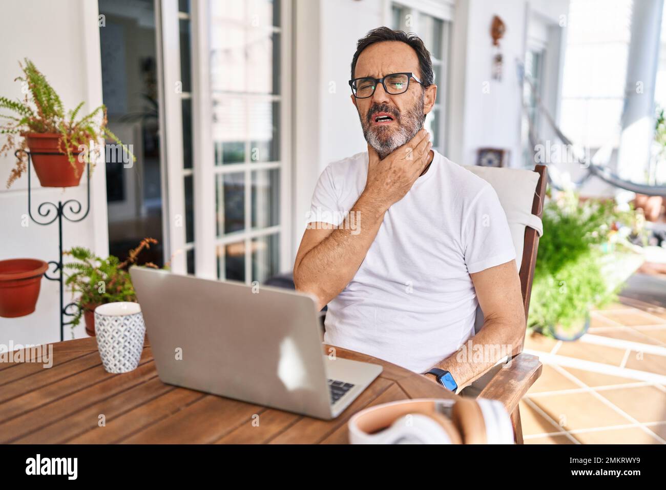 Middle age man using computer laptop at home touching painful neck ...