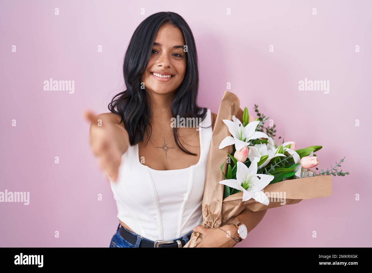 Brunette woman holding bouquet of white flowers smiling friendly ...