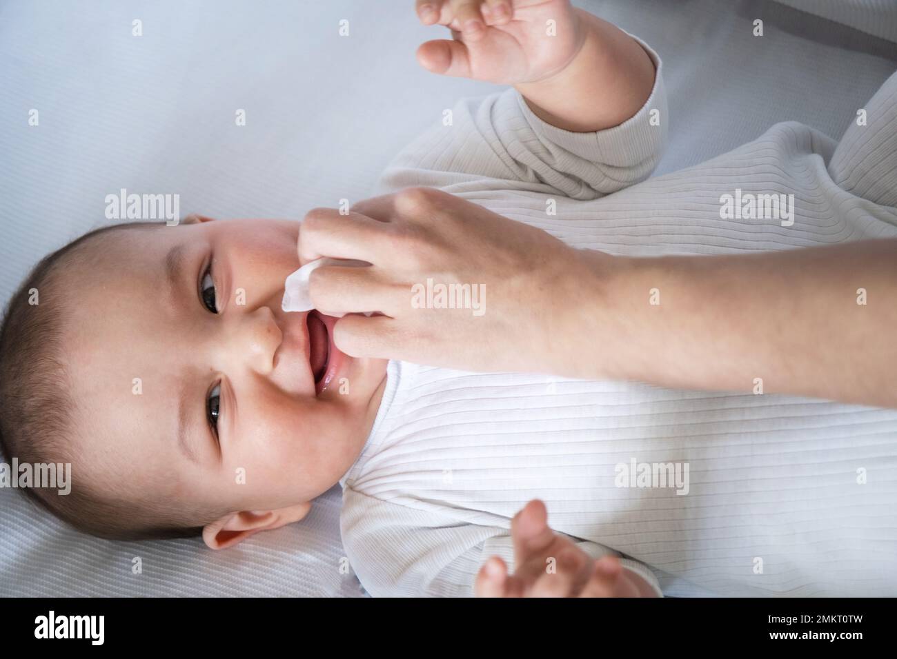 Mom wipes the baby's drool with a napkin. Baby care, teething, drooling ...