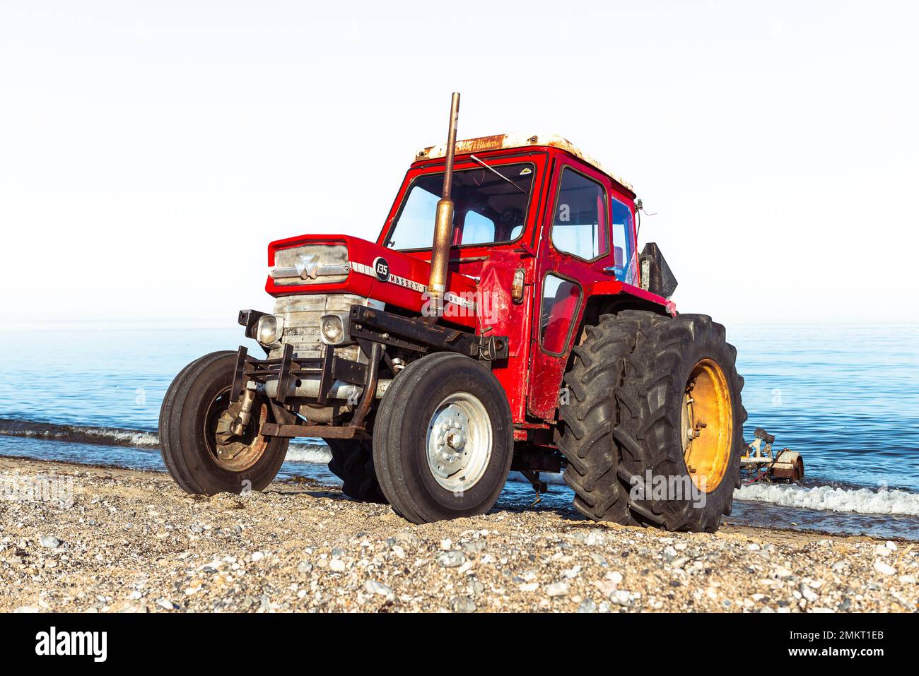An old, red Massey-Ferguson MF 135 tractor stands with an empty boat ...