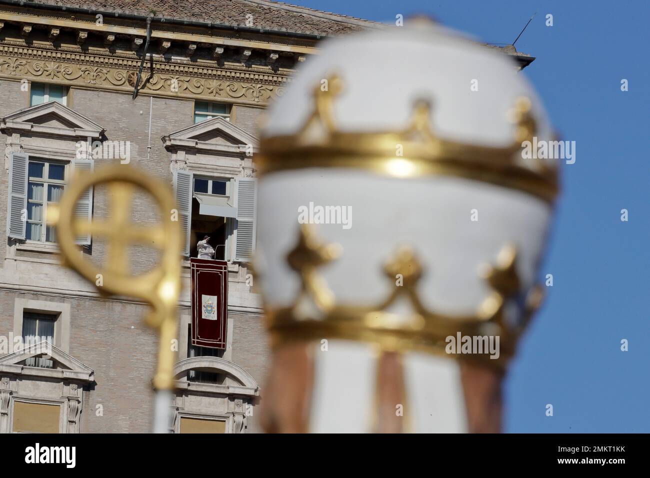 Pope Francis is framed by a statue as he recites the Angelus noon ...
