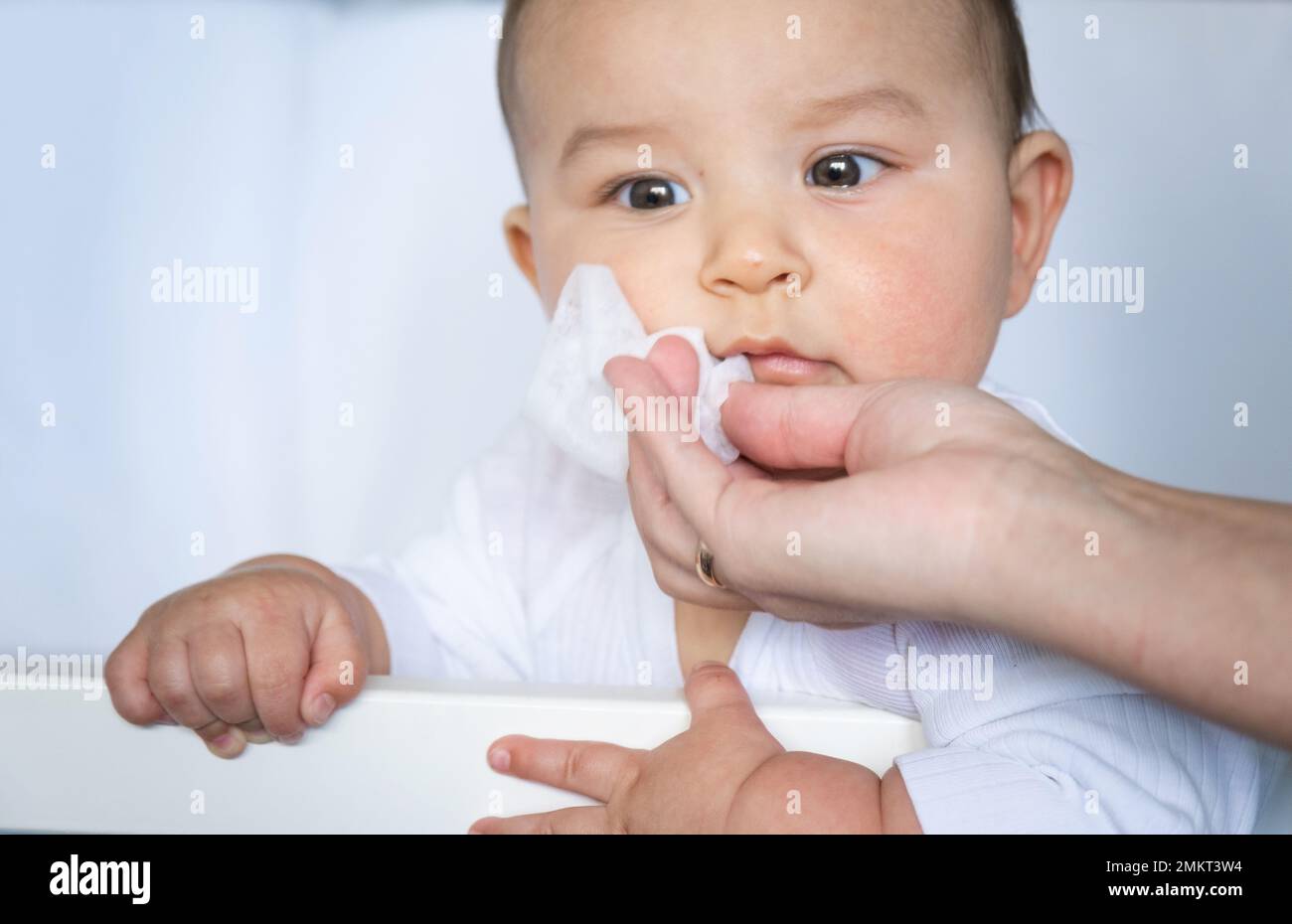 Mom wipes the baby's drool with a napkin. Baby care, teething, drooling ...