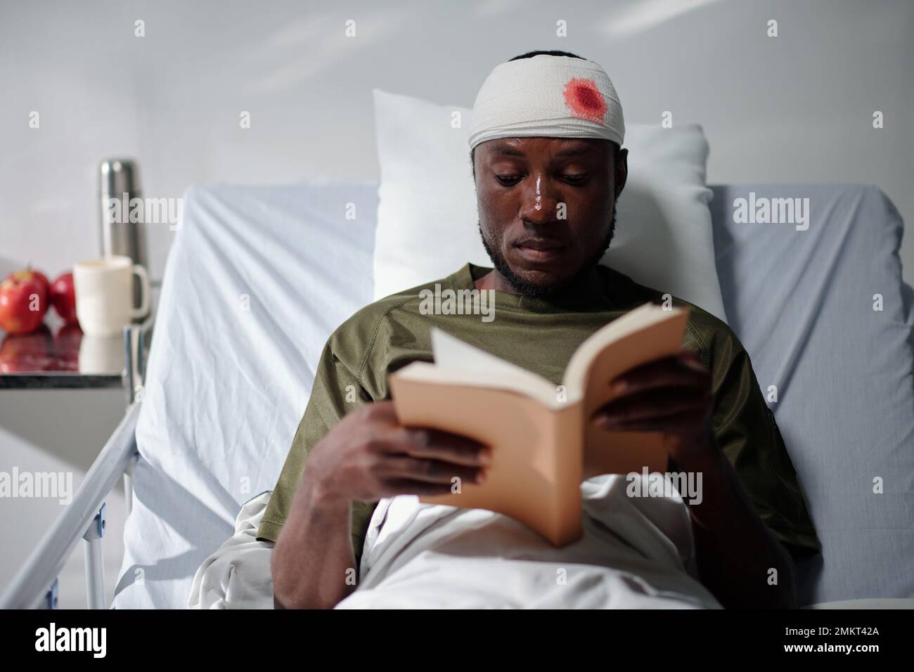 Sick military man reading good book when spending time in hospital ...
