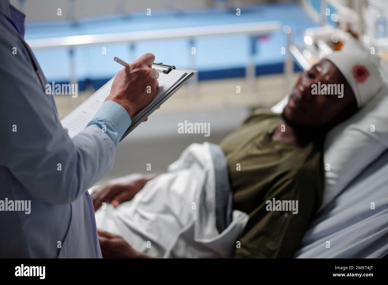 Surgeon talking to sick injured military man and filling medical form ...