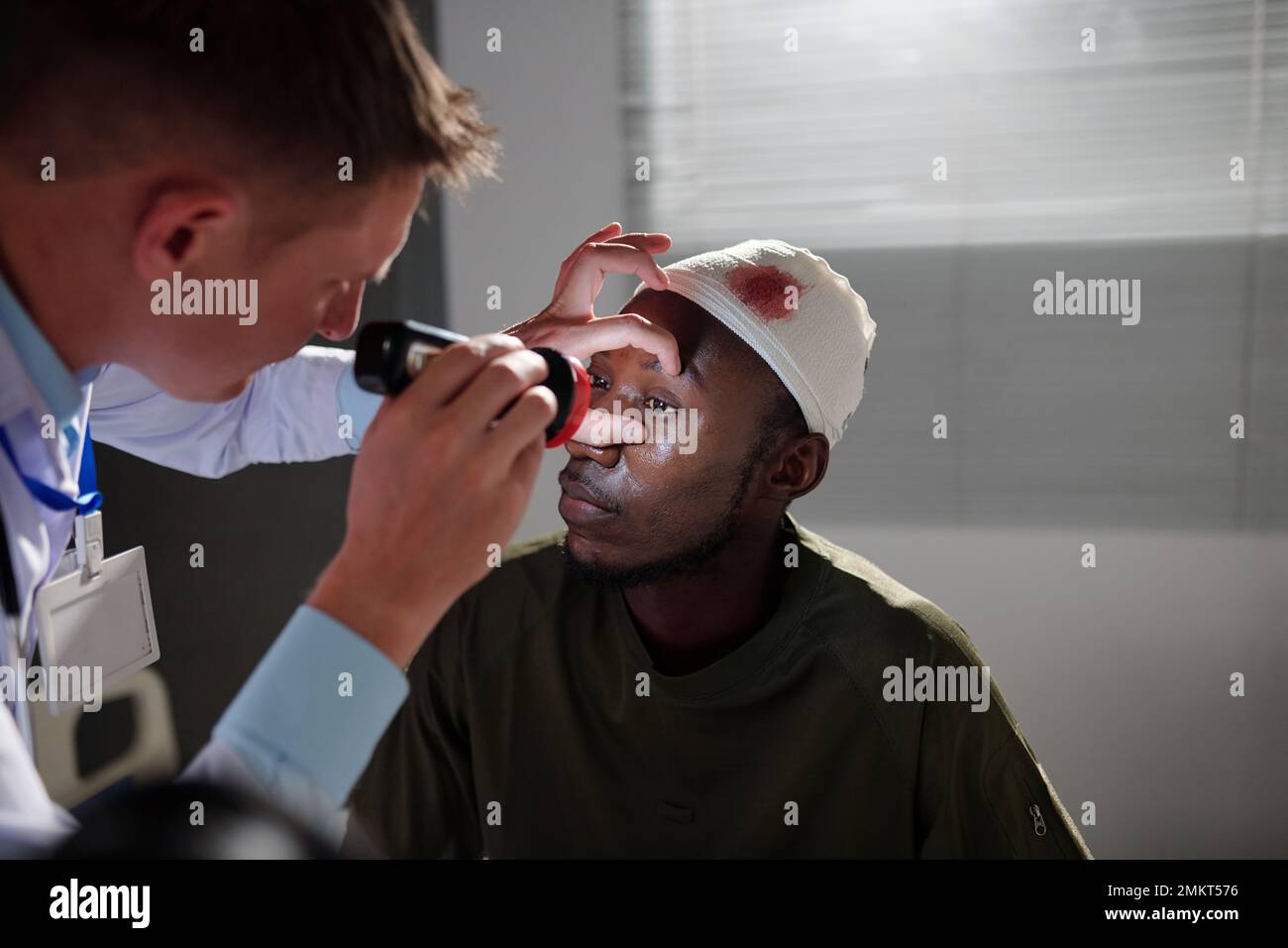 Military man with brain injury looking at beam of light when doctor ...