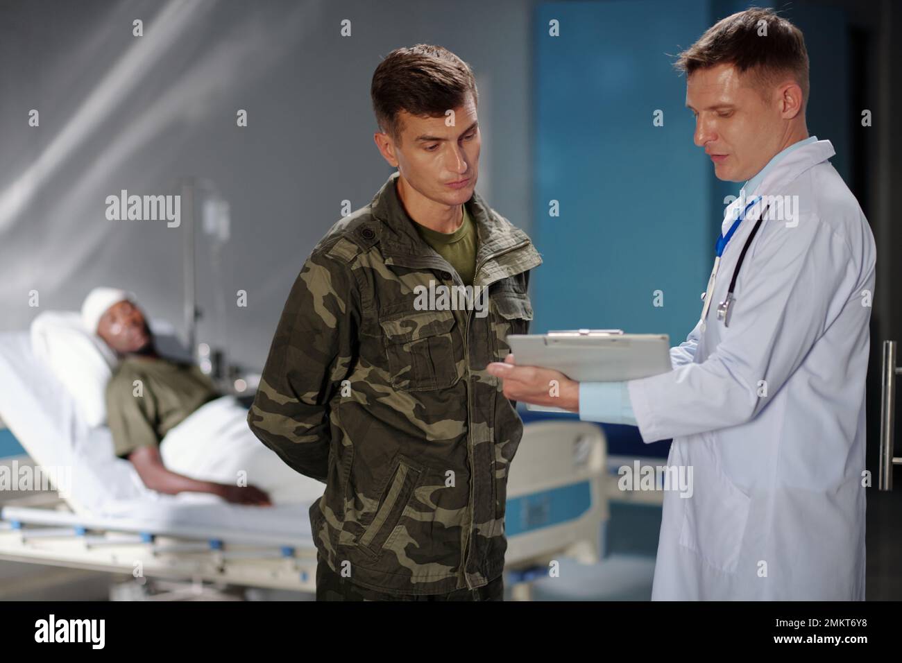 Doctor showing medical test results to sergeant of injured soldier ...