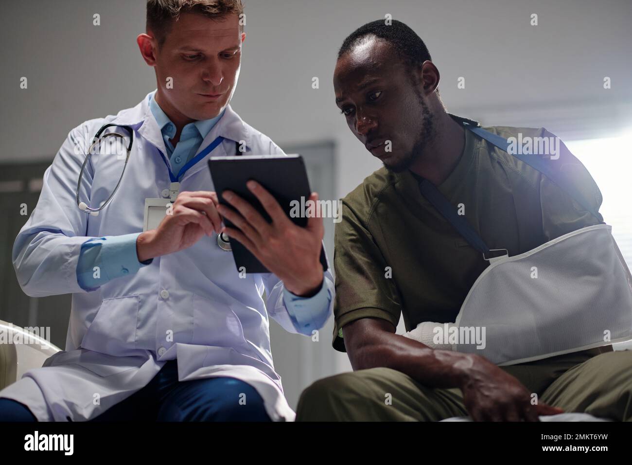 Doctor showing x-ray image of broken arm to injured soldier Stock Photo ...