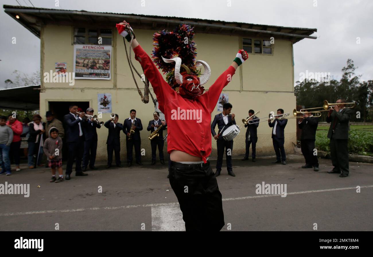 Revelers wearing colorful devil masks dance in the streets of Pillaro ...