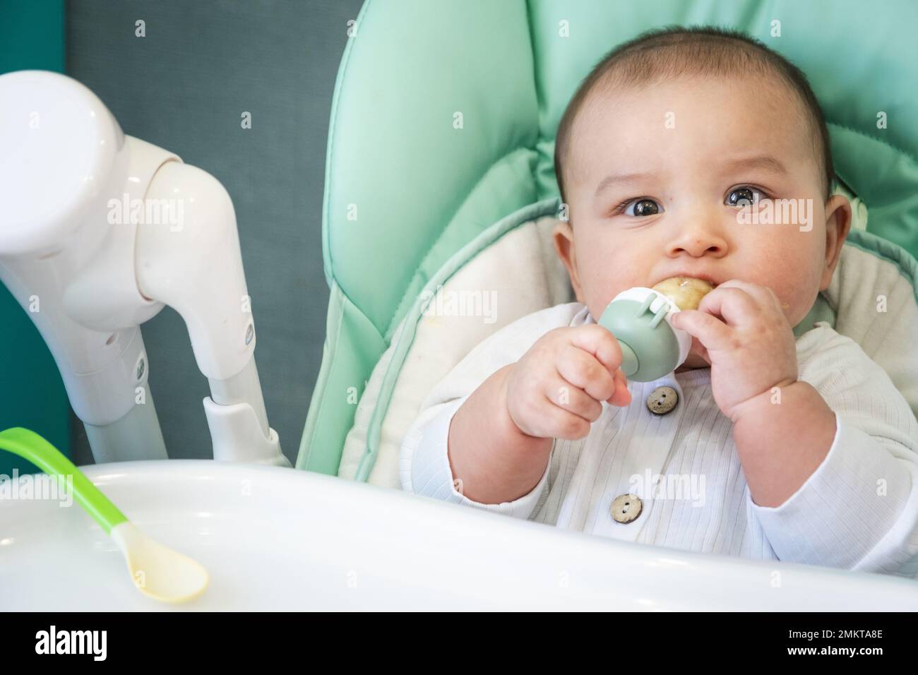 A happy and contented baby eats banana puree from a nipple ...