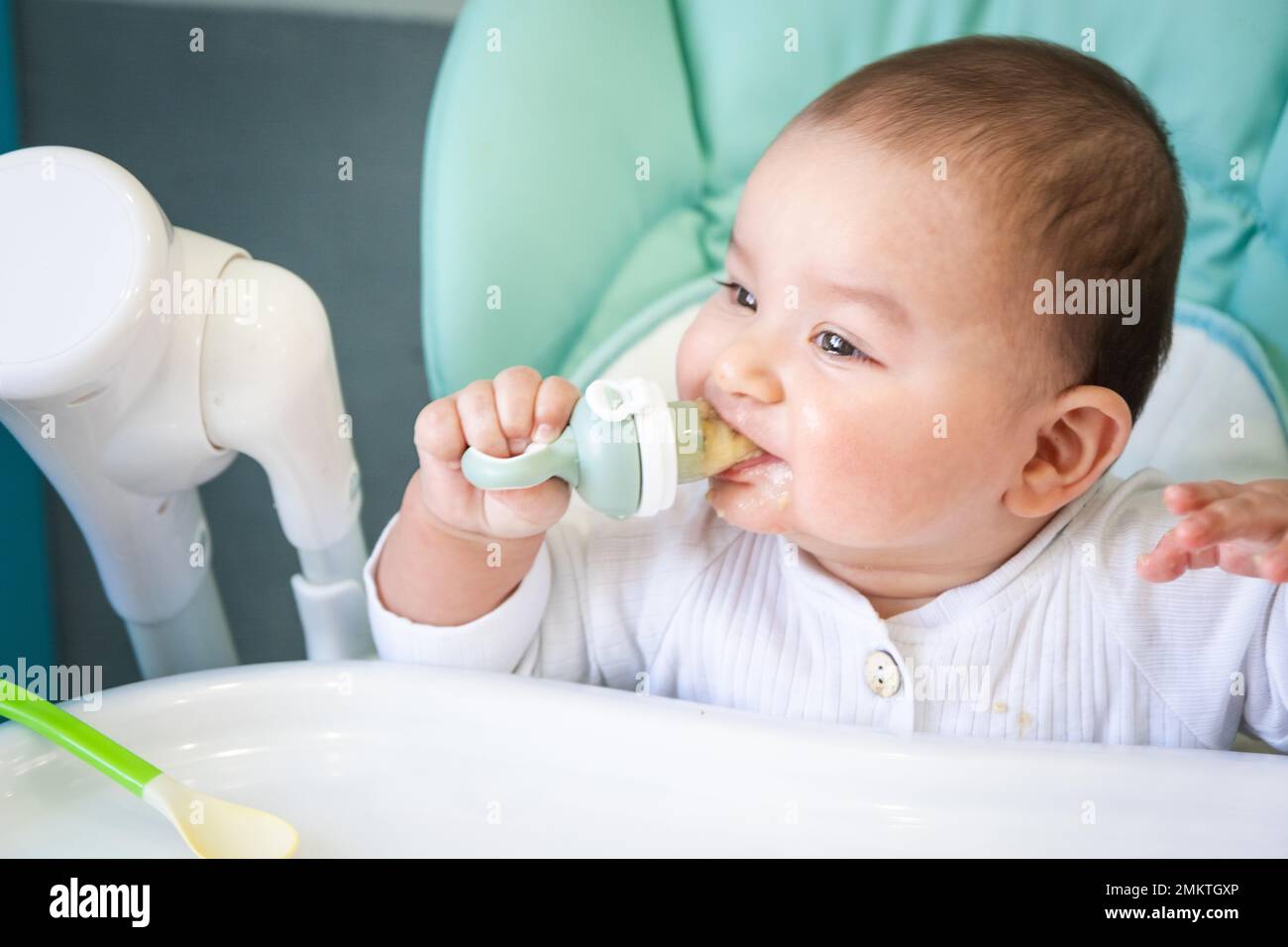 A happy and contented baby eats banana puree from a nipple ...
