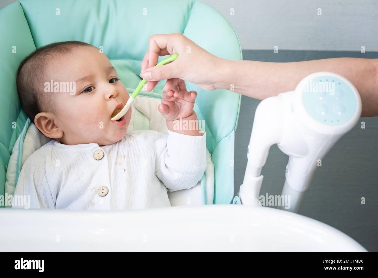 Mom feeds the baby with a spoon of vegetable puree at the children's ...