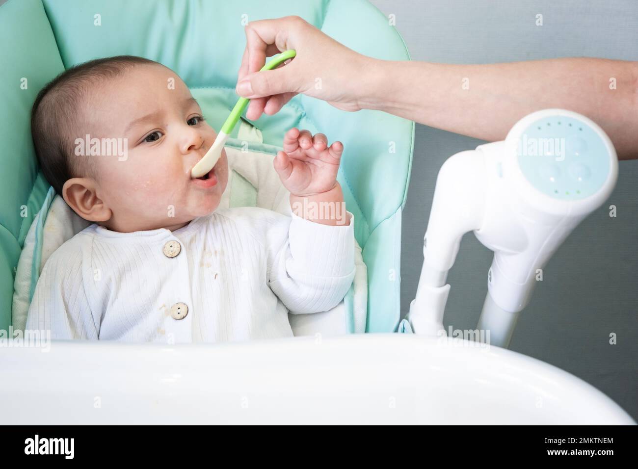 Mom feeds the baby with a spoon of vegetable puree at the children's ...