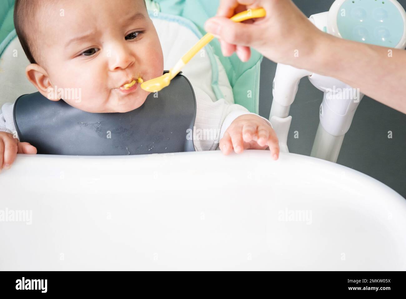 Mom feeds the baby with a spoon of vegetable puree at the children's ...
