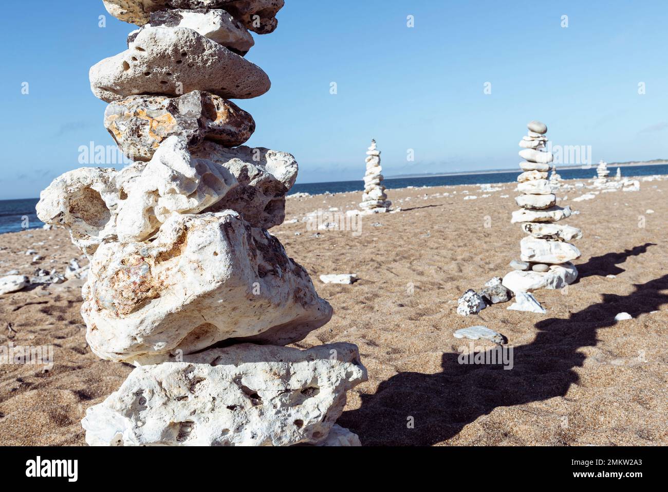 Cairns of flint stones standing on the sandy beach of Klitmöller on the ...