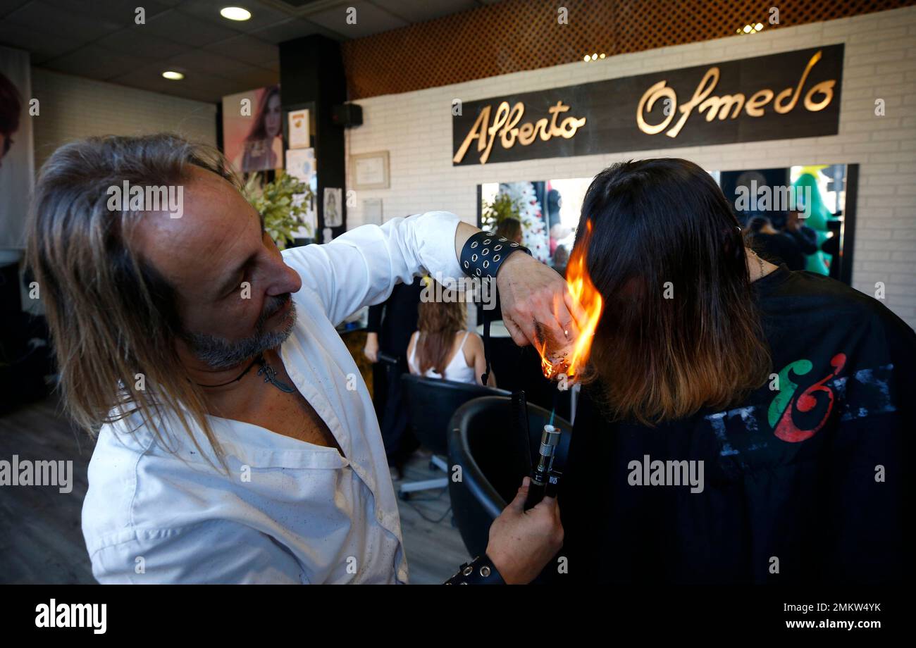 Hairdresser Alberto Olmedo demonstrates cutting a woman's hair with a ...