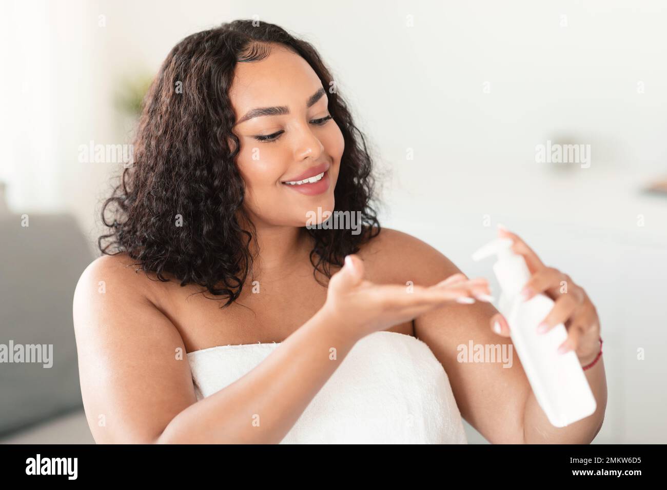Black oversize woman holding bottle and pouring moisturising body ...