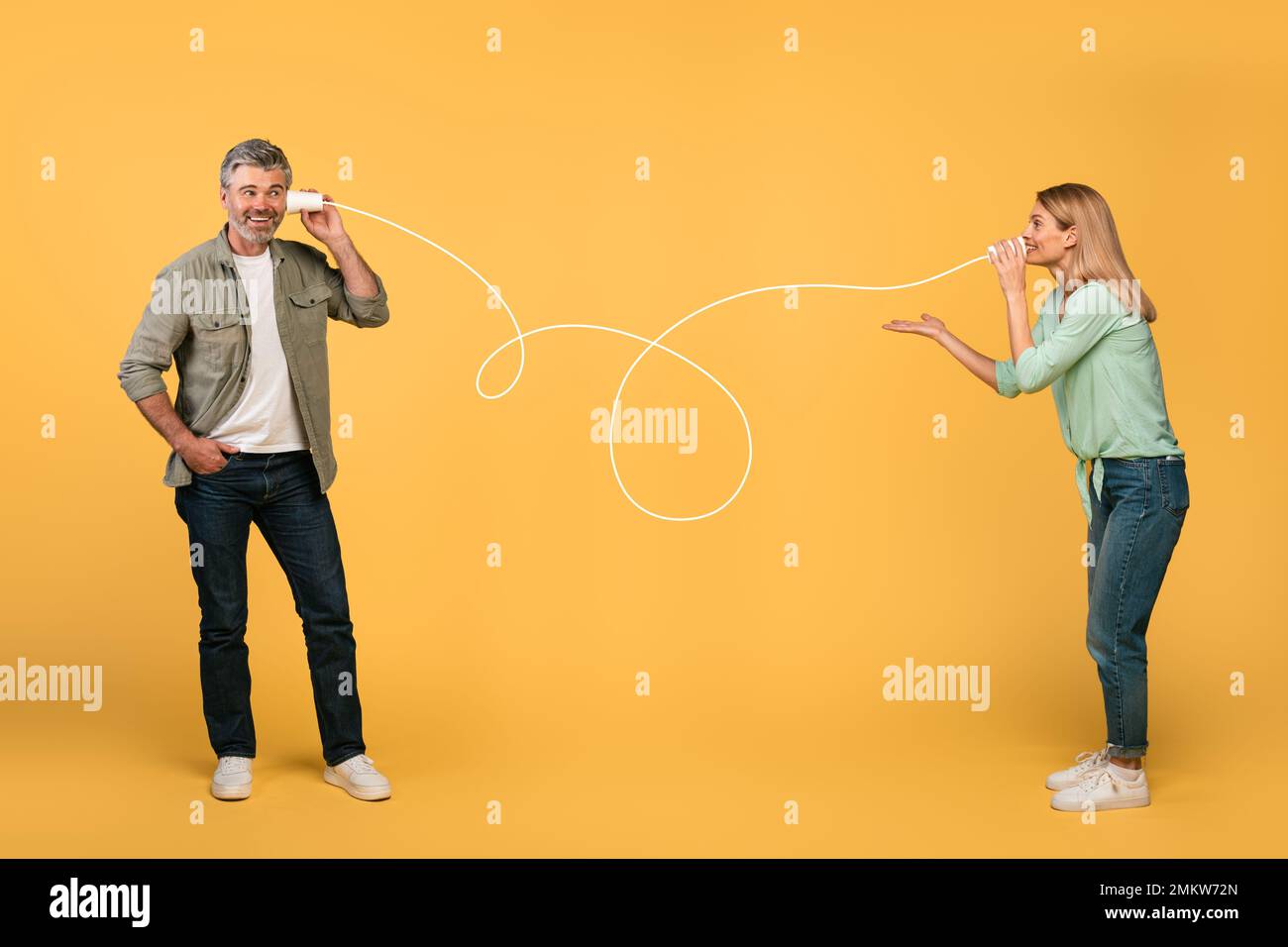 Communication and fun. Happy middle aged spouses talking through tin ...