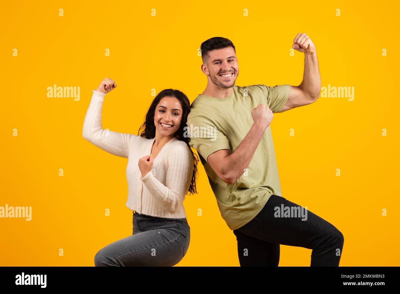 Cheerful excited young arabic couple in casual make gesture of success ...