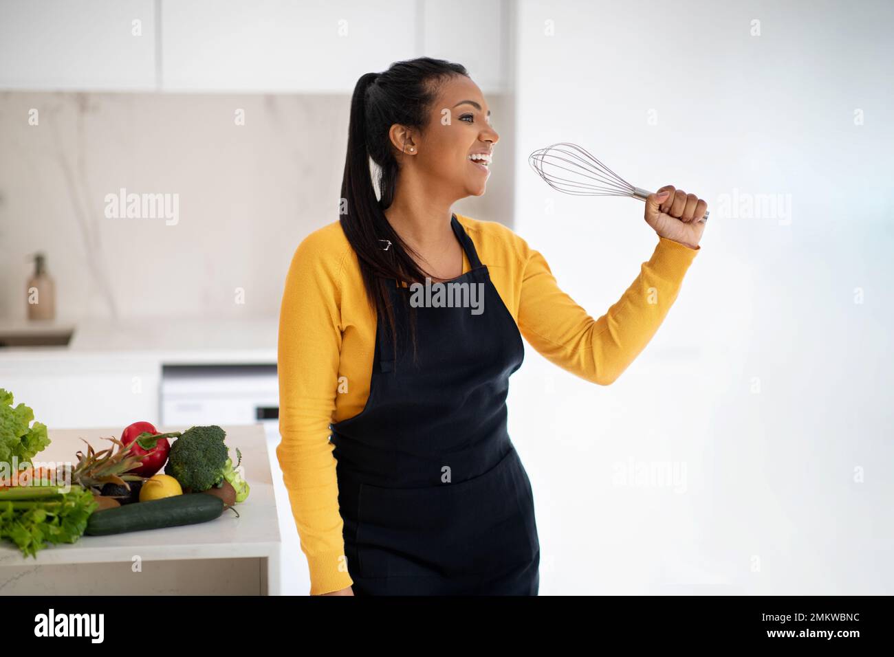 Happy millennial african american female superstar in apron singing at ...