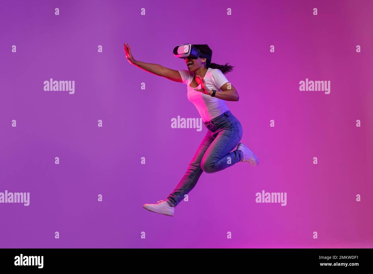 Excited Black Woman Wearing VR Glasses Jumping In Air In Neon Light ...
