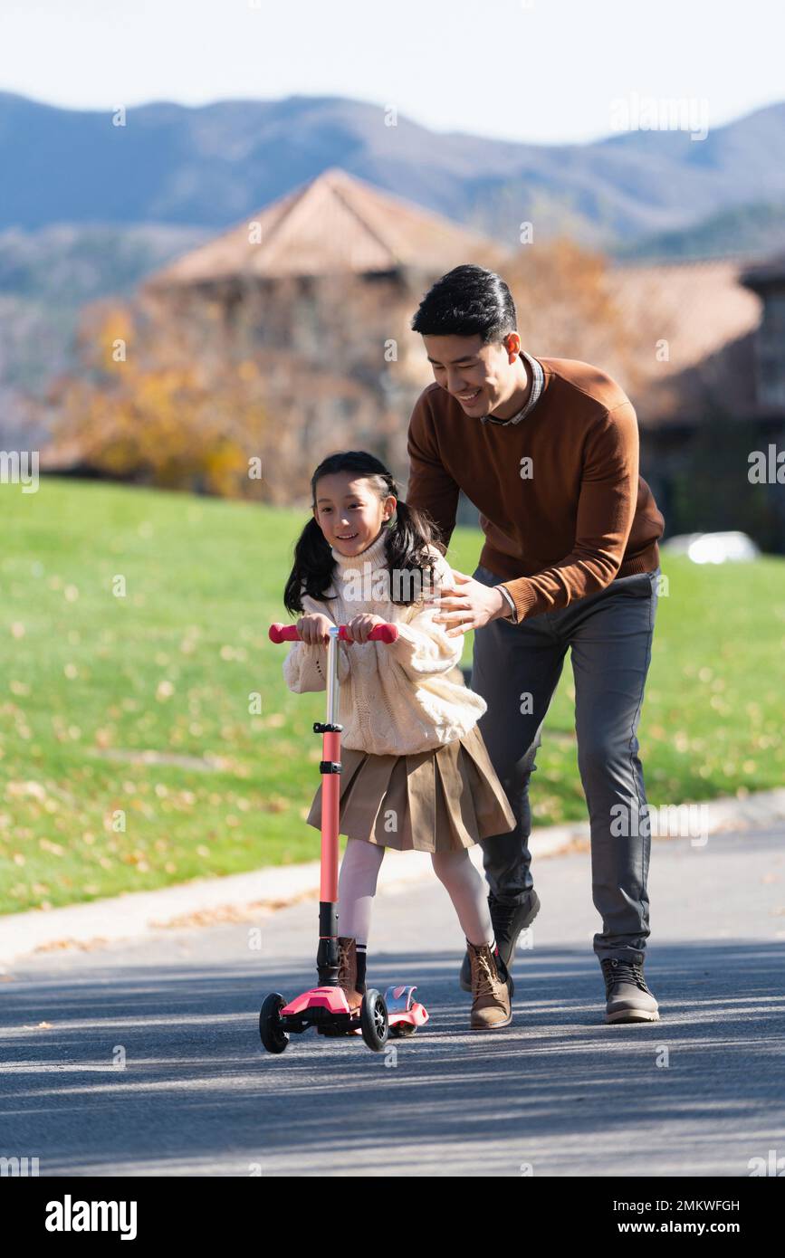 Father with children playing scooter Stock Photo - Alamy