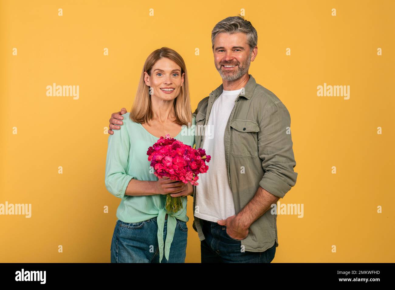 Happy middle aged couple holding bouquet of flowers and hugging ...