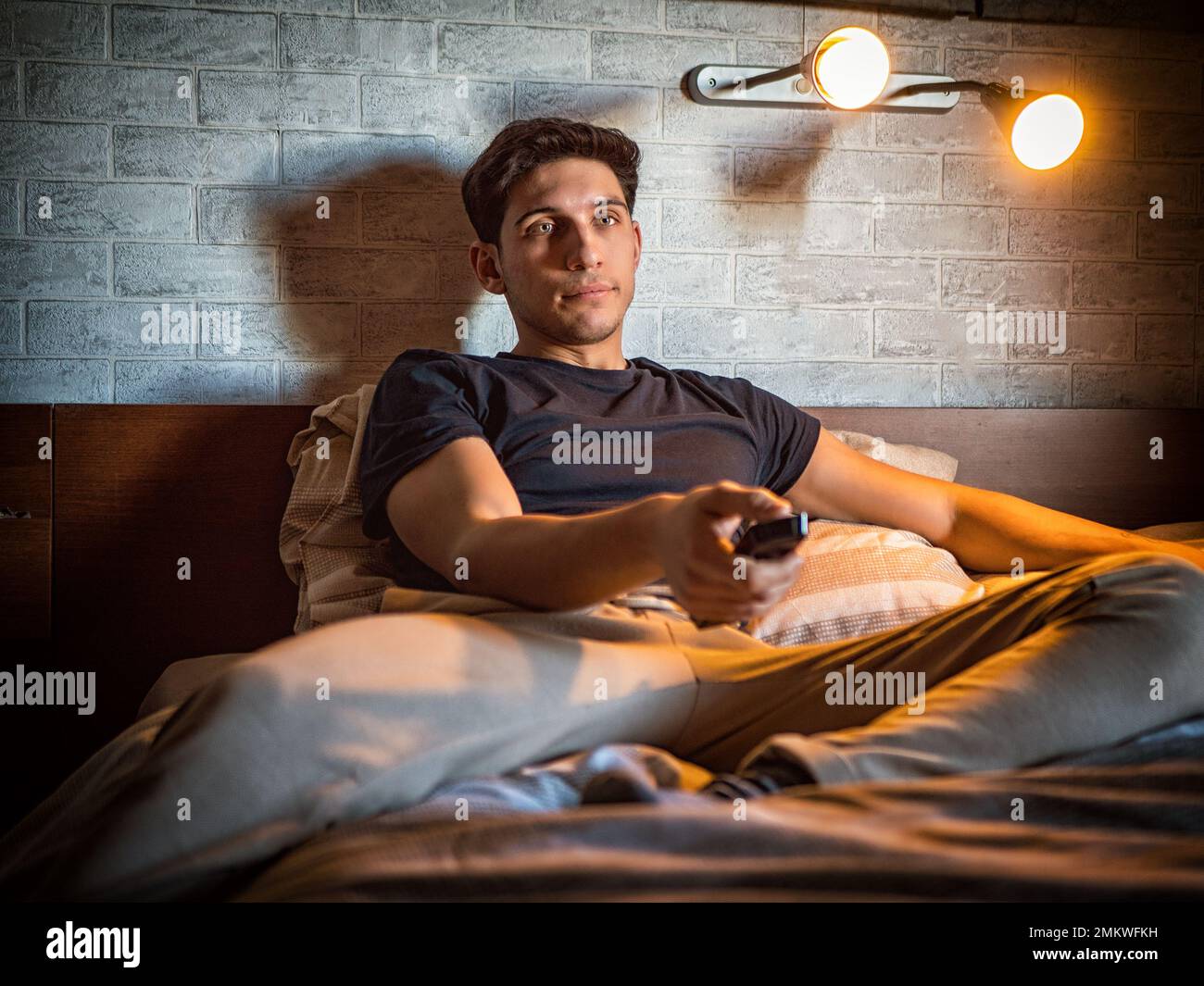 Handsome young man laying on his bed watching TV Stock Photo - Alamy