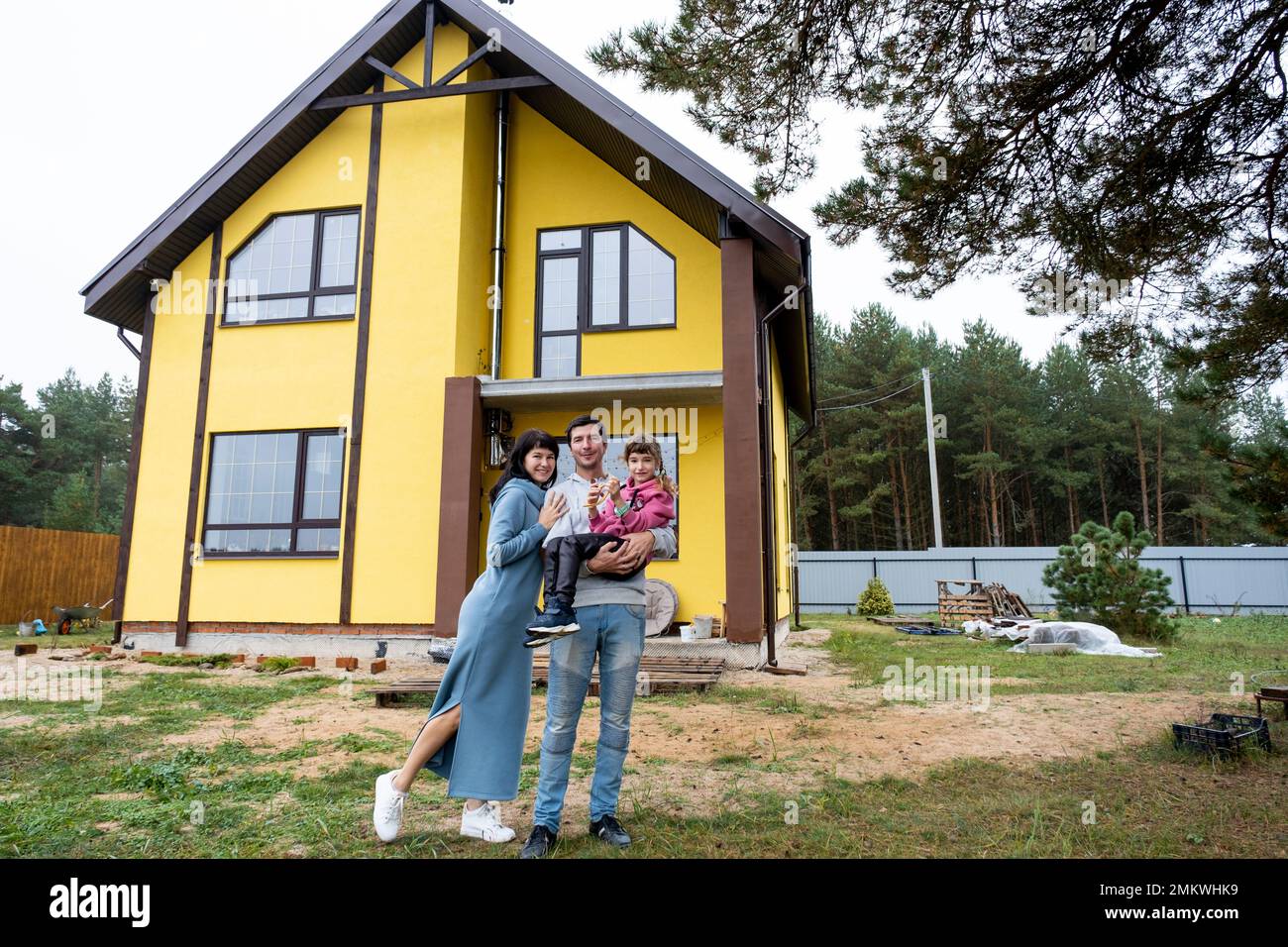 Happy family in the yard of an unfinished house - purchase of a cottage ...