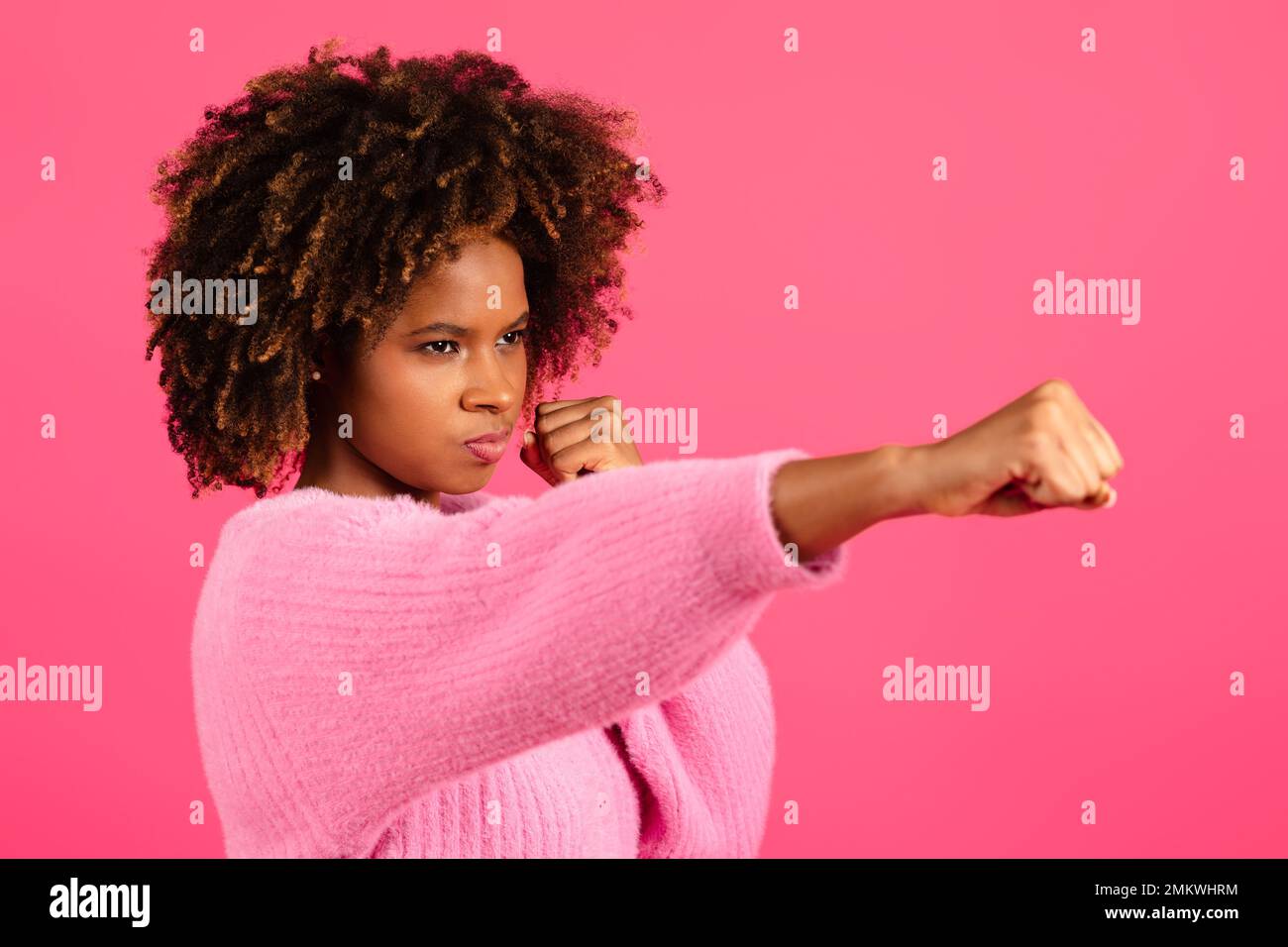 Serious confident young black curly female do hand punch isolated on ...