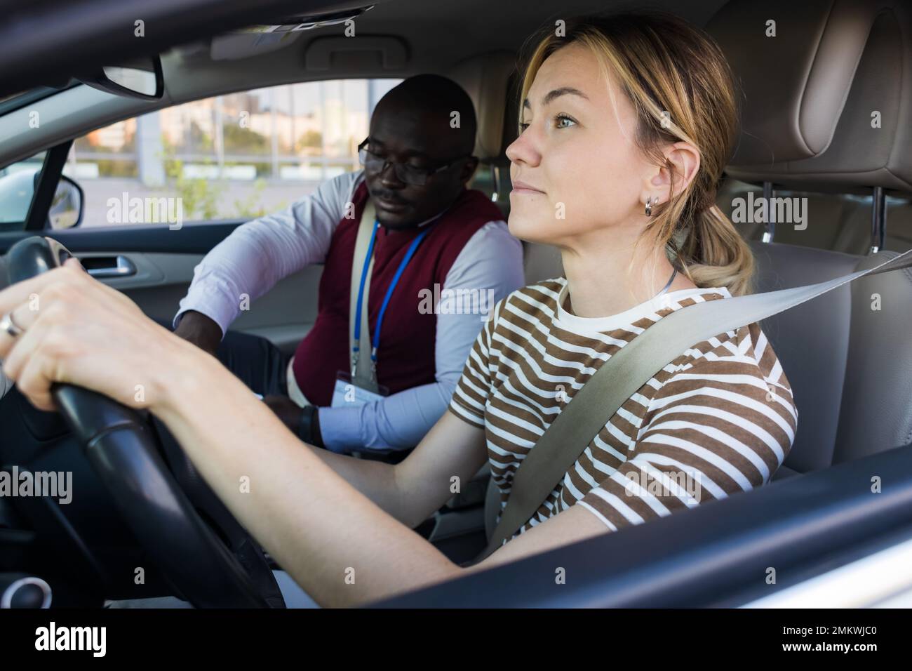 Driving school concept. A car instructor teaches a young woman how to ...