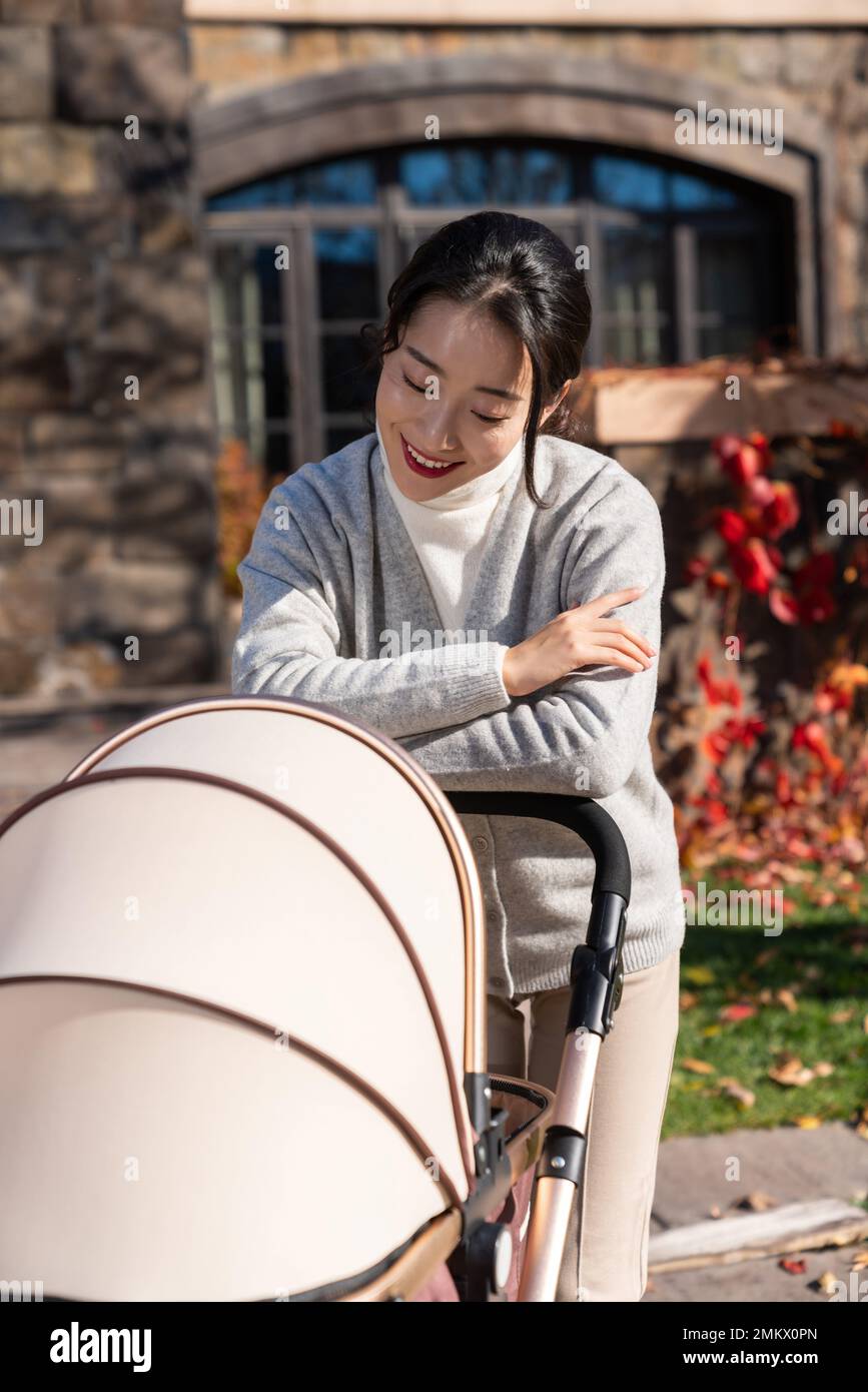 Young mother pushing a stroller for a walk Stock Photo - Alamy