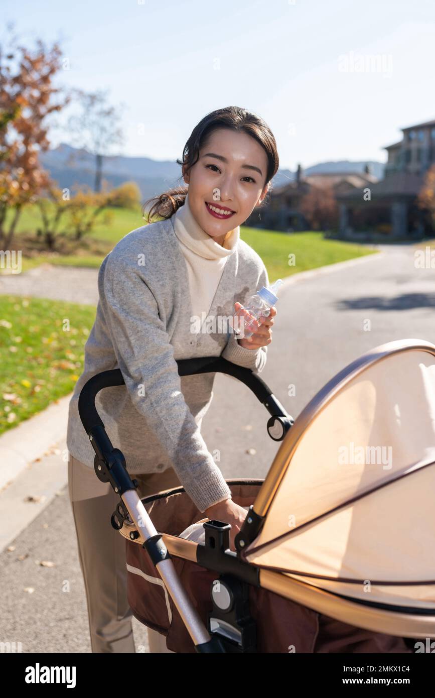 Young mother pushing a stroller for a walk Stock Photo - Alamy