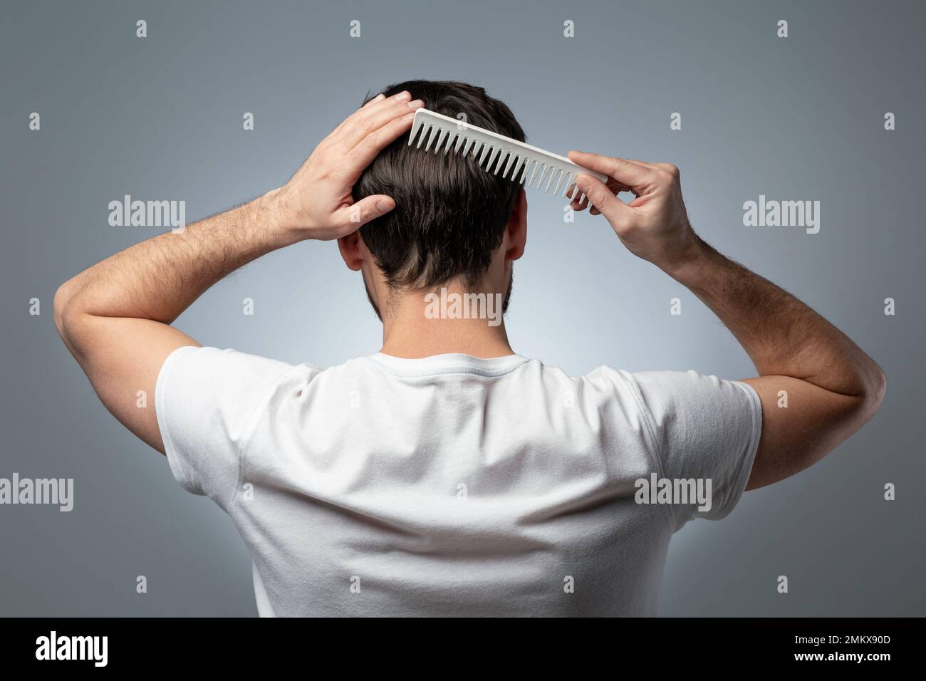 Hair care concept. Back view of unrecognizable man hairbrushing with ...