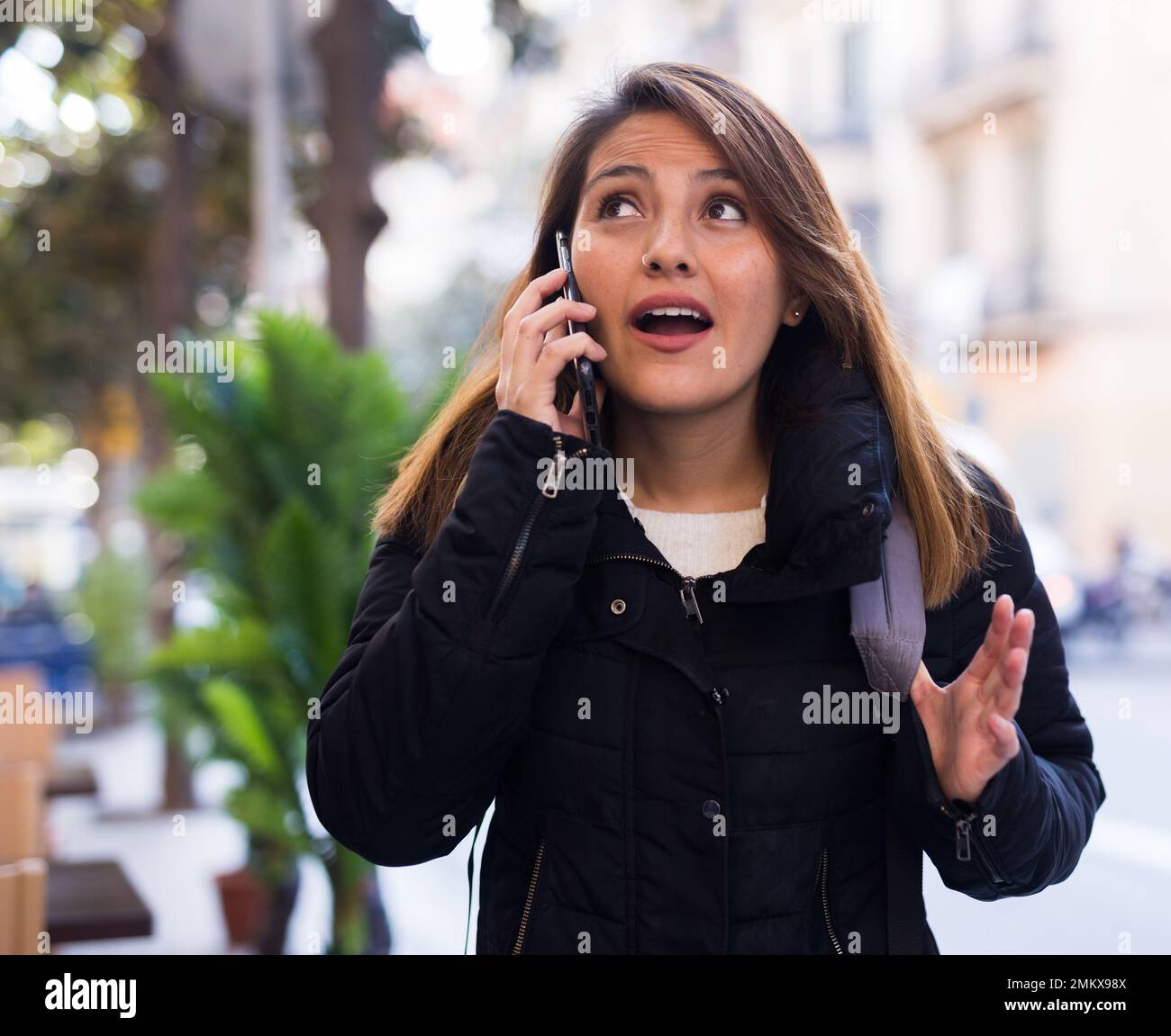 Happy girl talking on phone while walking along city street Stock Photo ...