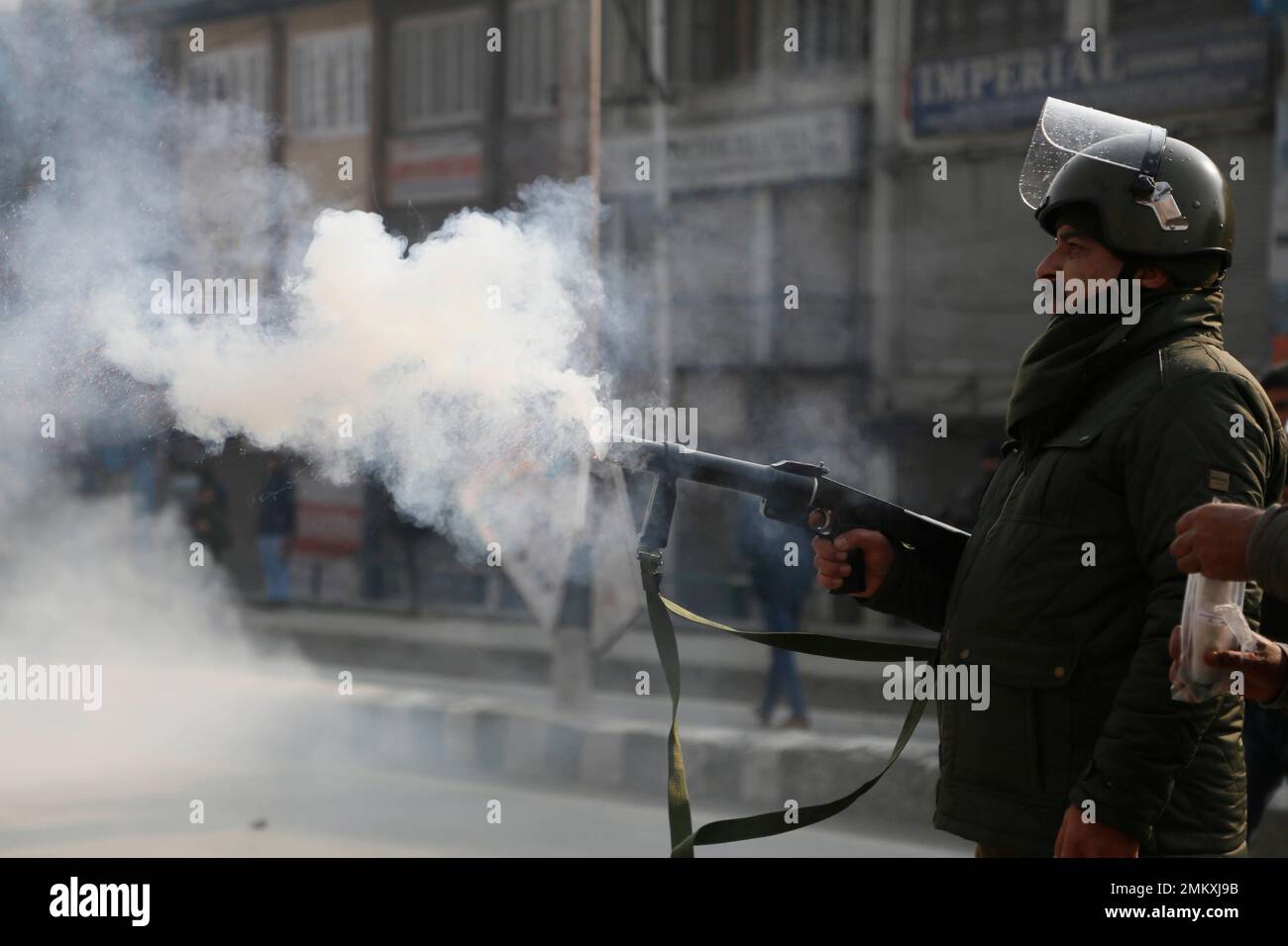 An Indian police officer fires tear smoke shell on Kashmiri protesters ...