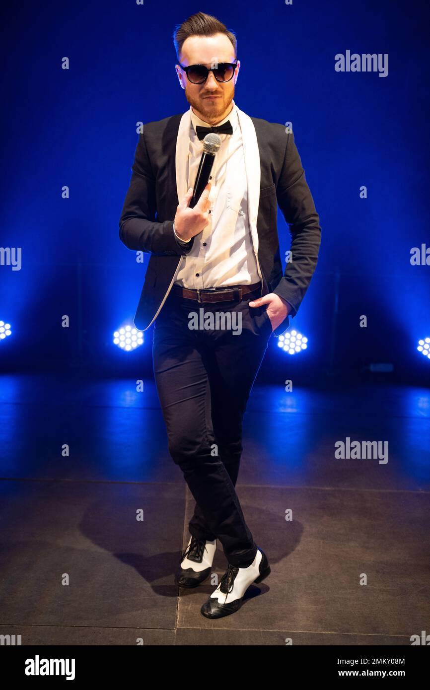 handsome presenter and showman in a stylish suit with a microphone on ...