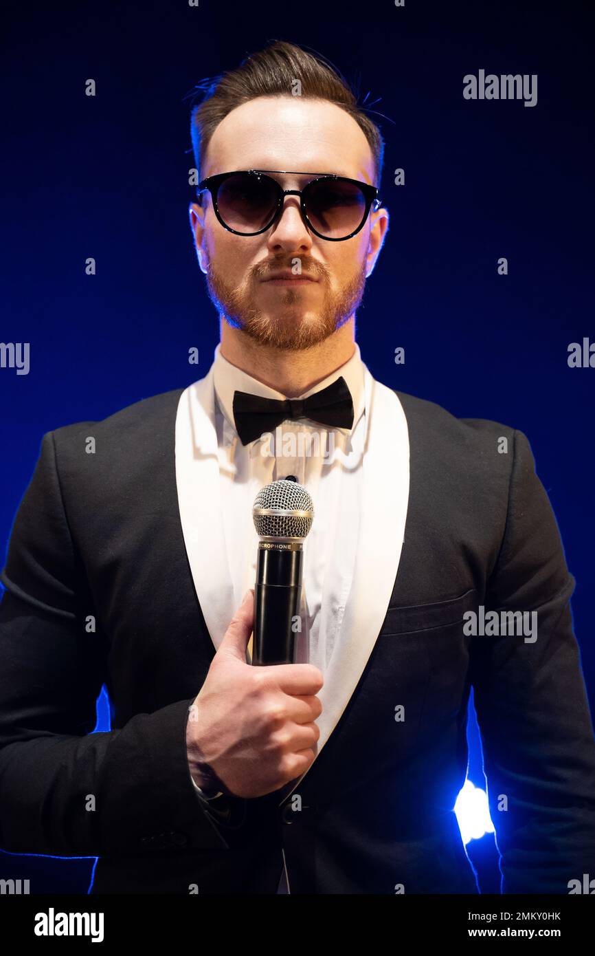 handsome presenter and showman in a stylish suit with a microphone on ...