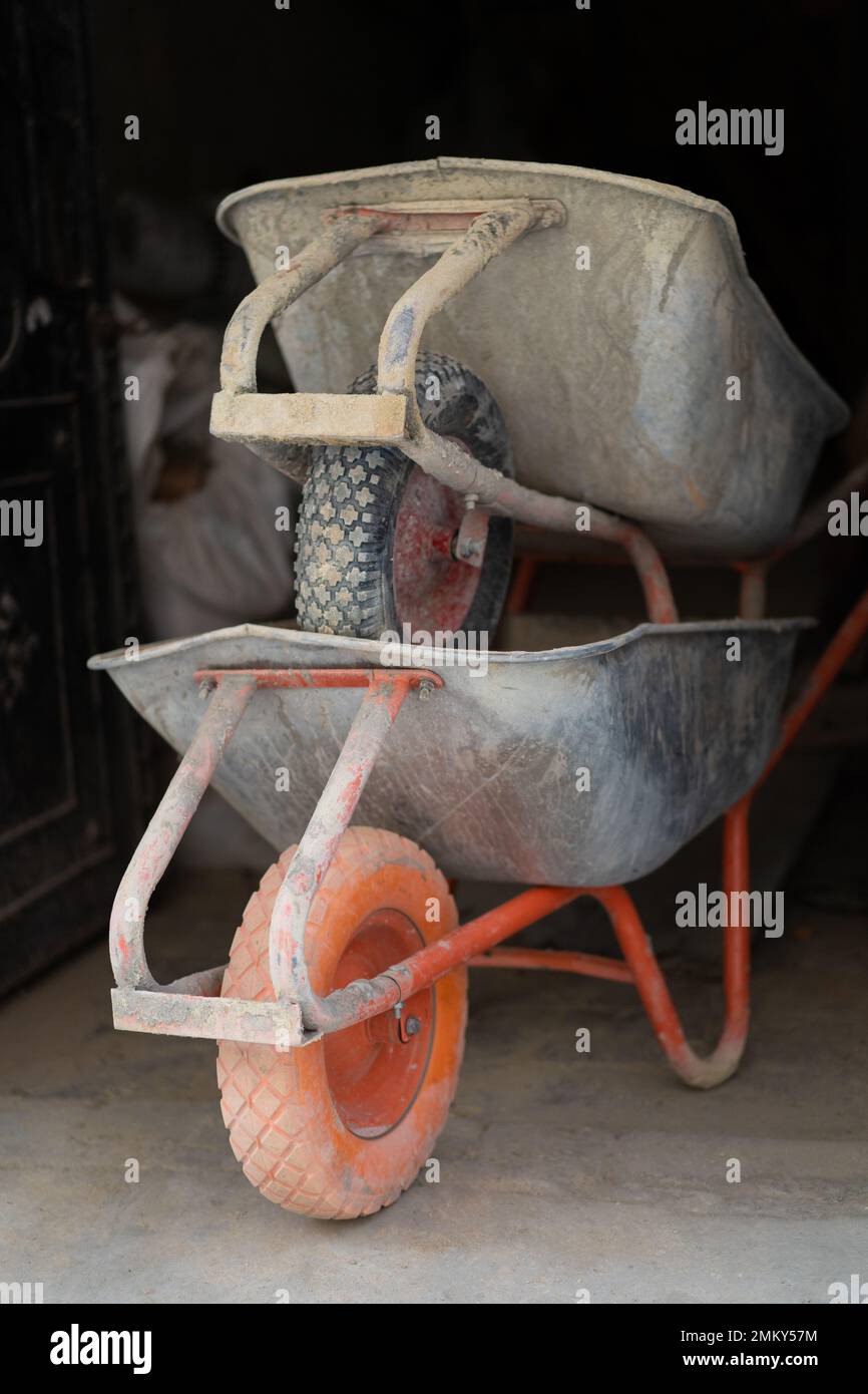 A metal wheelbarrow with one wheel used by workers in construction or ...