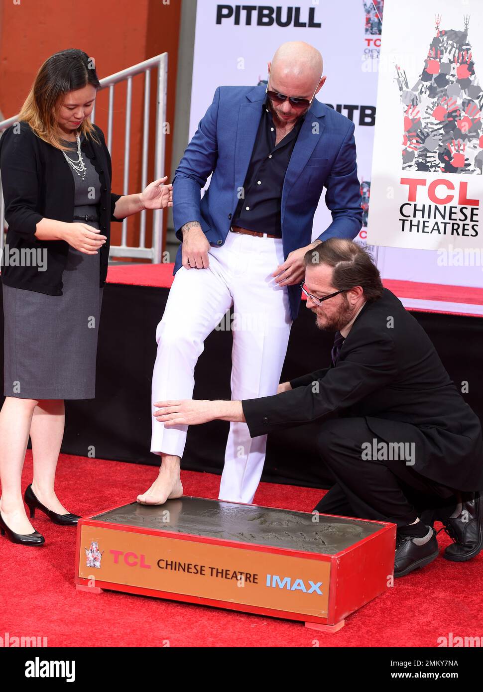 Event staff help Pitbull place his feet in cement during a hand and ...
