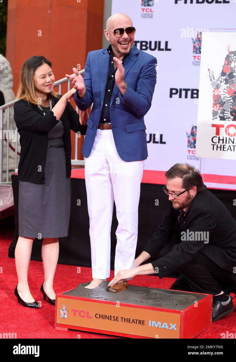 Event staff help Pitbull place his feet in cement during a hand and ...