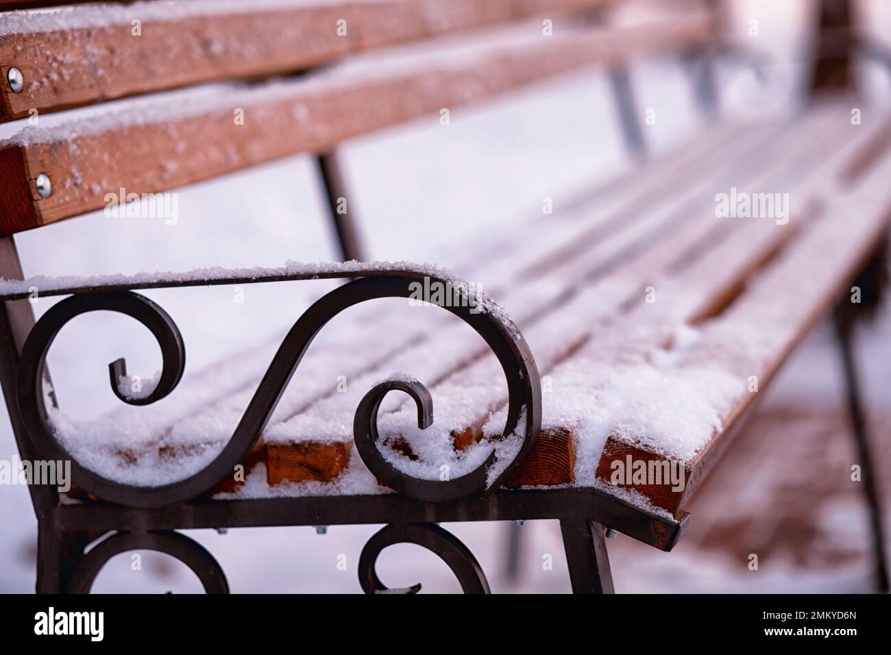 park bench on a winter alley at snowfall. bench with snow after ...