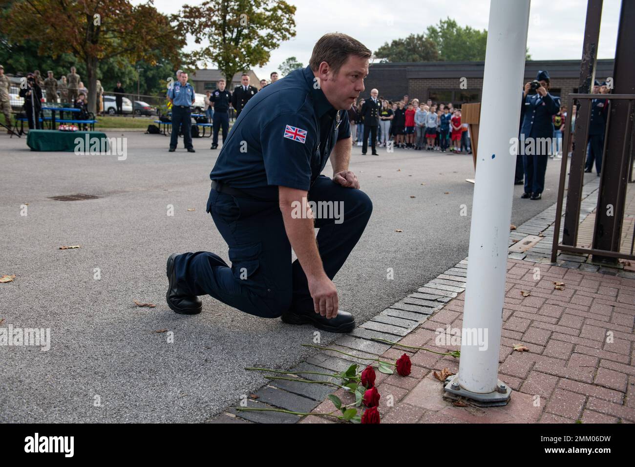 A member of the fire department places a rose at the base of a flagpole ...