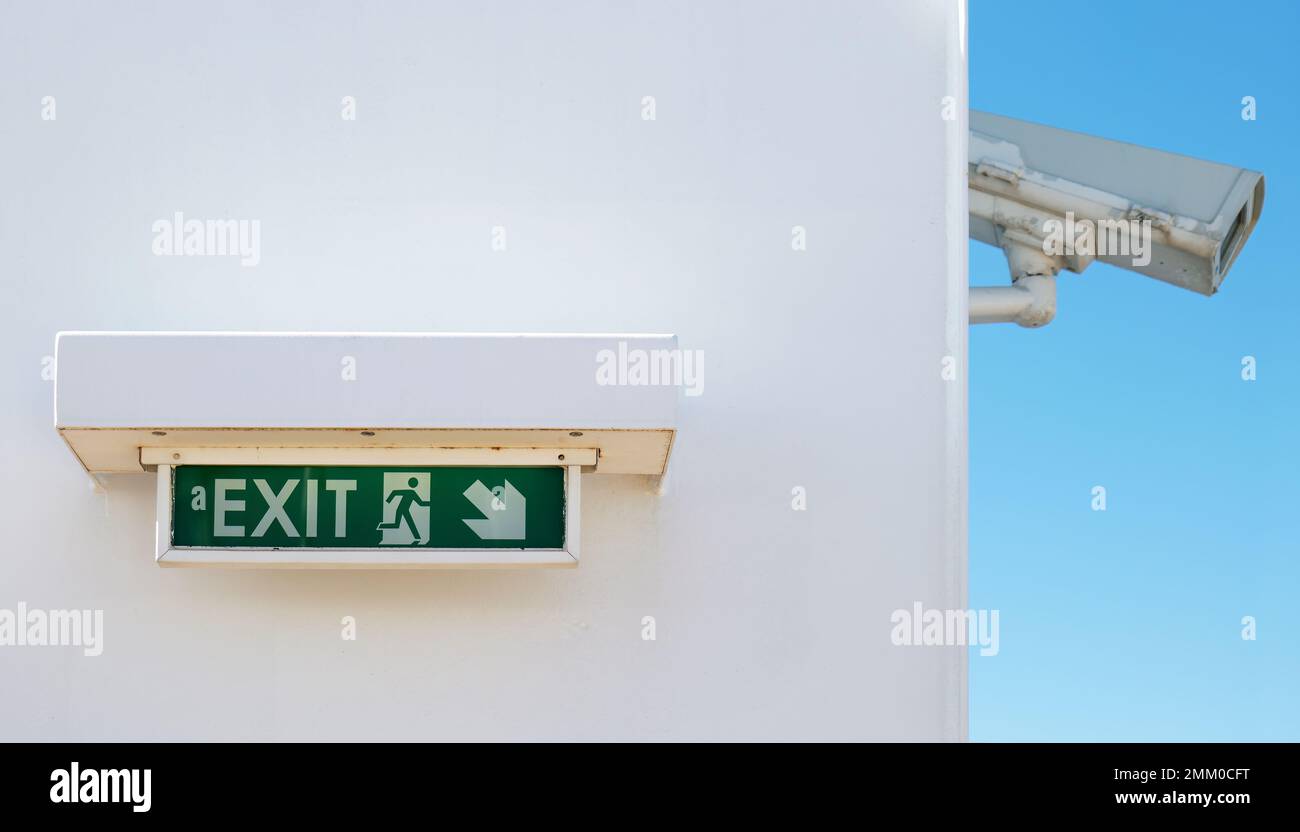 Emergency exit sign on wall with camera in background Stock Photo - Alamy