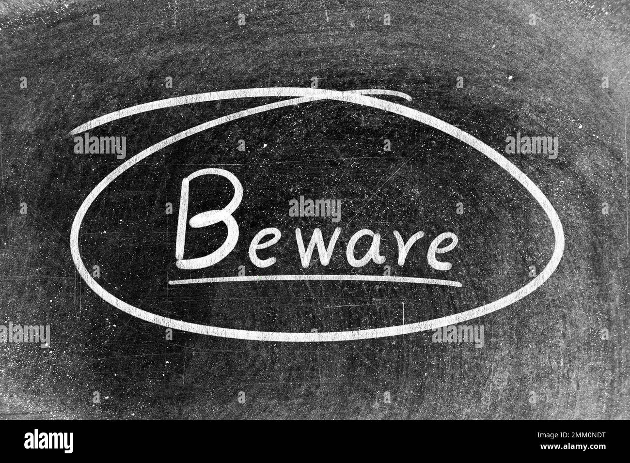 White chalk hand writing in word beware and circle shape on blackboard ...