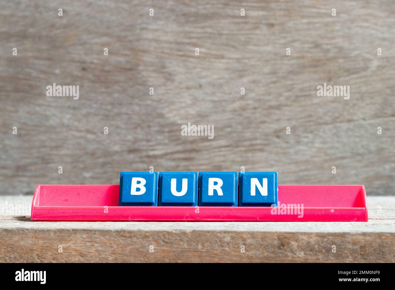 Tile letter on red rack in word burn on wood background Stock Photo - Alamy