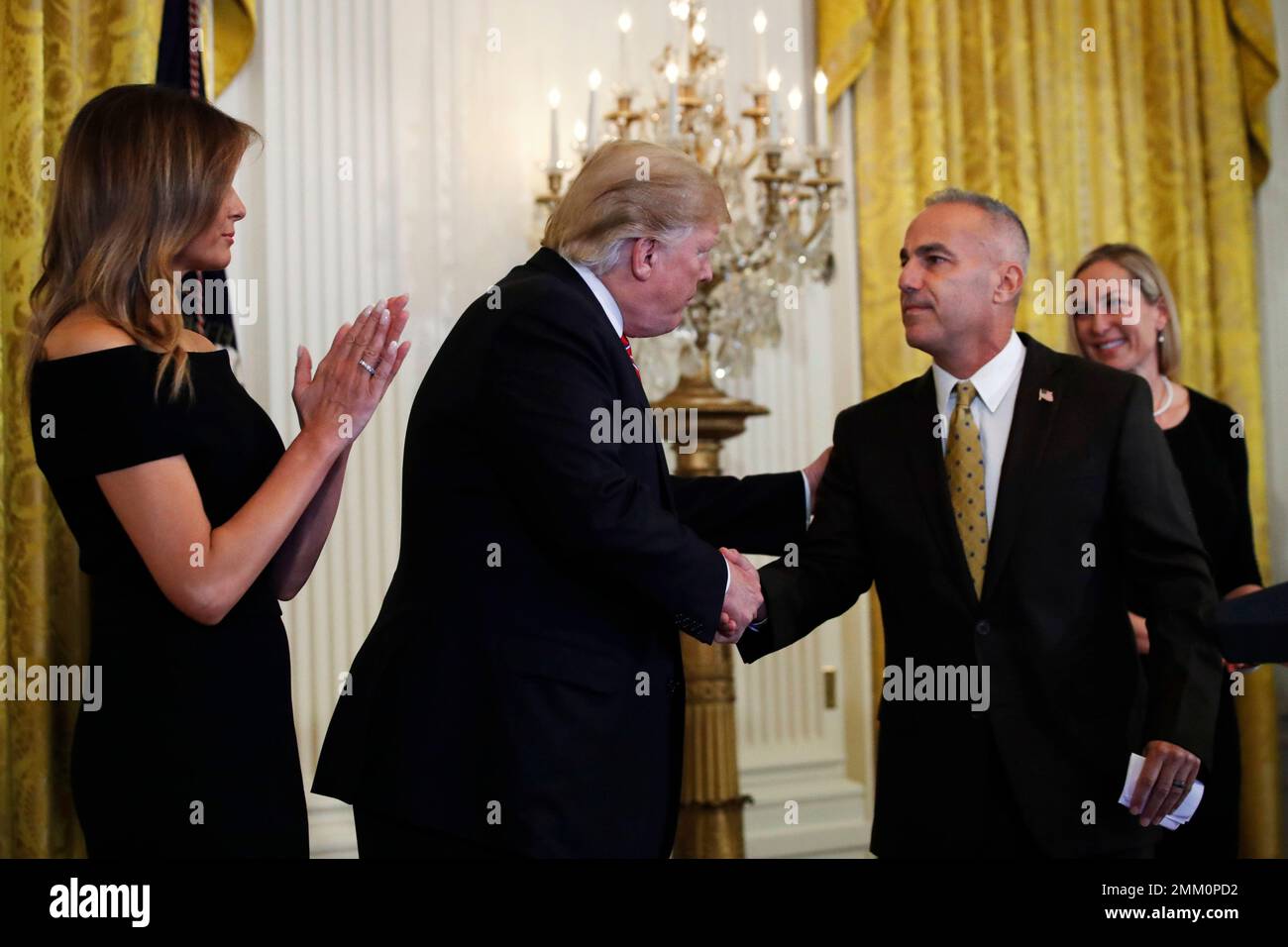 As first lady Melania Trump applauds, President Donald Trump shakes ...