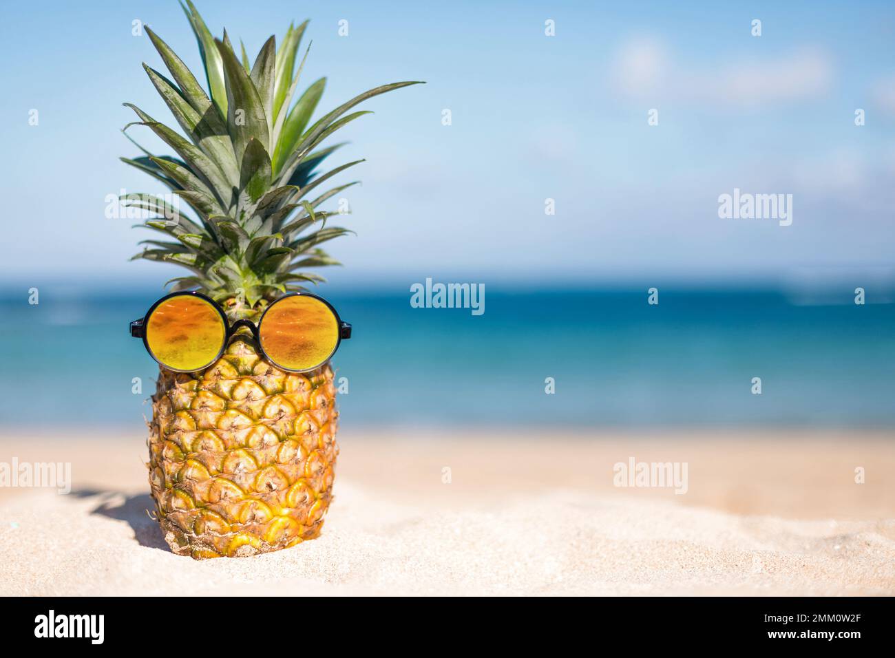 Pineapple on the beach with blue sky and sea background Stock Photo - Alamy