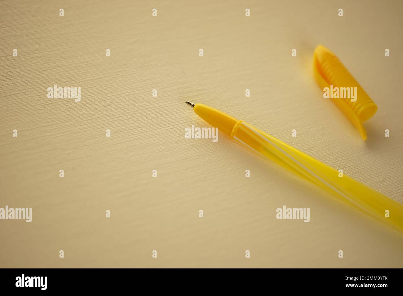 Yellow ball pen and cap closeup on a beige paper Stock Photo - Alamy
