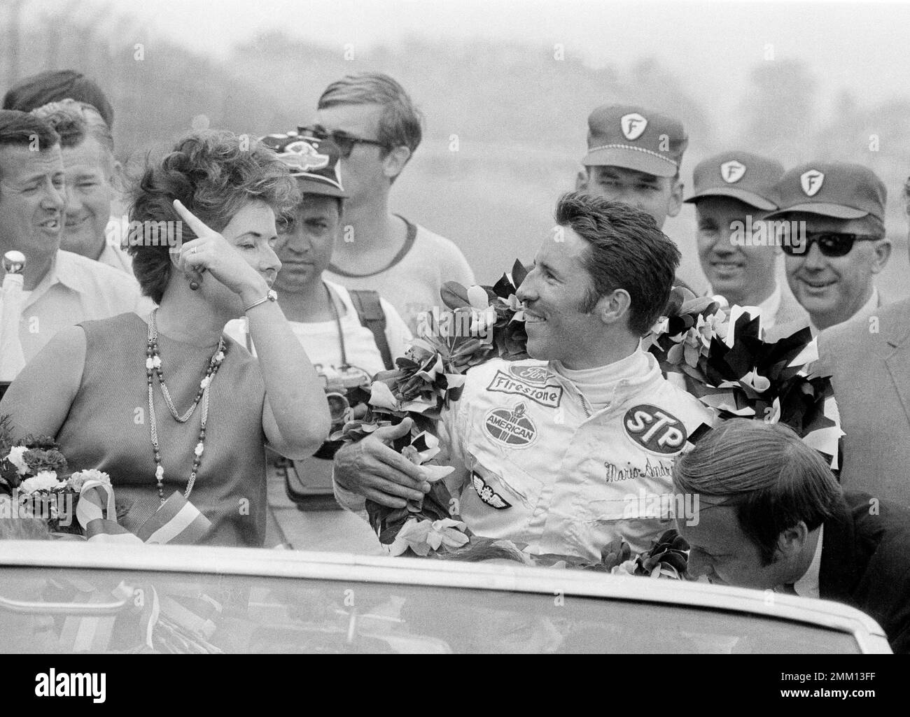 Mario Andretti of Nazareth, Penn., with a garland of flowers around his ...